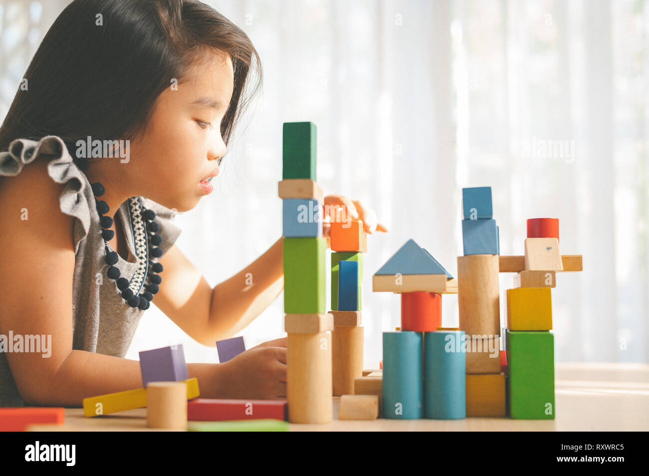 little girl in a colorful shirt playing with construction toy blocks ...