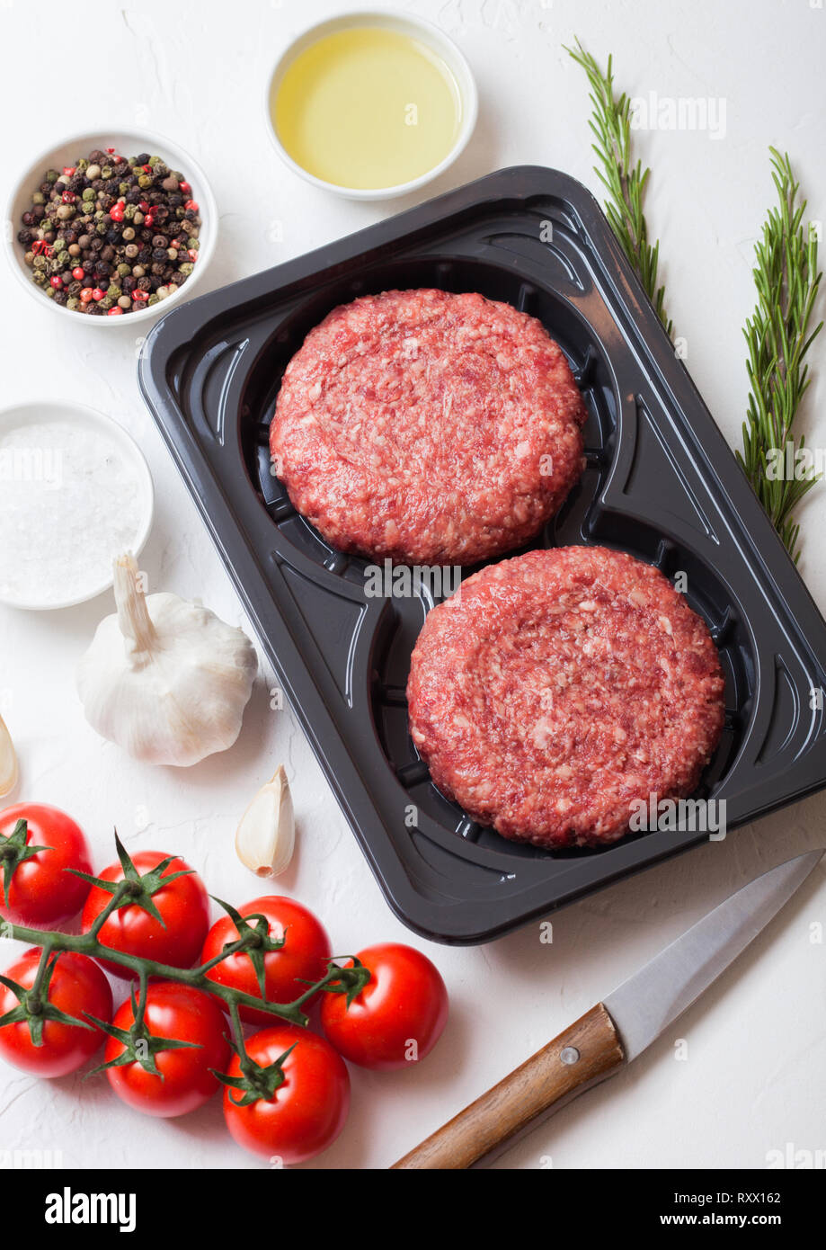 Plastic tray with raw minced homemade grill beef burgers with spices ...
