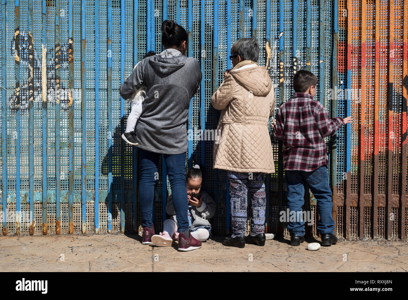 Family at the Tijuana border, talking with relatives, a girl is ...