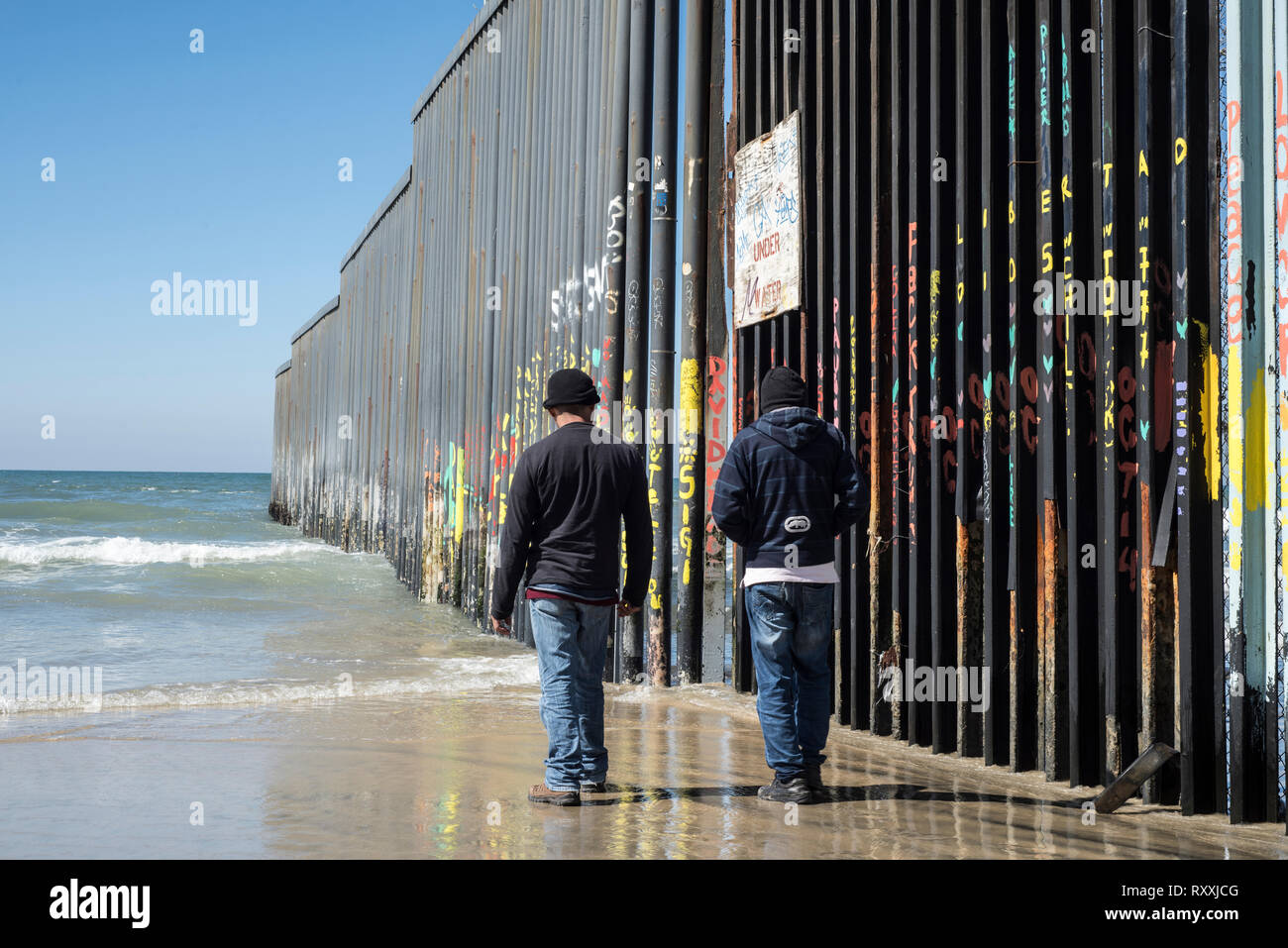 Two men satanding at Tijuana beach, gazing at the other side of the ...