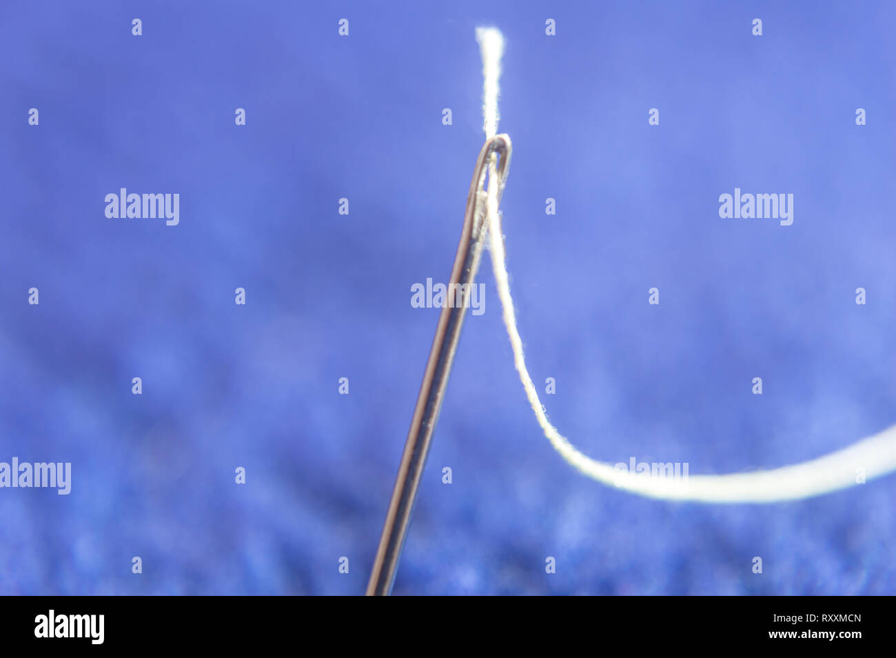 Zoomed in shot of a thread passing through a needle Stock Photo - Alamy