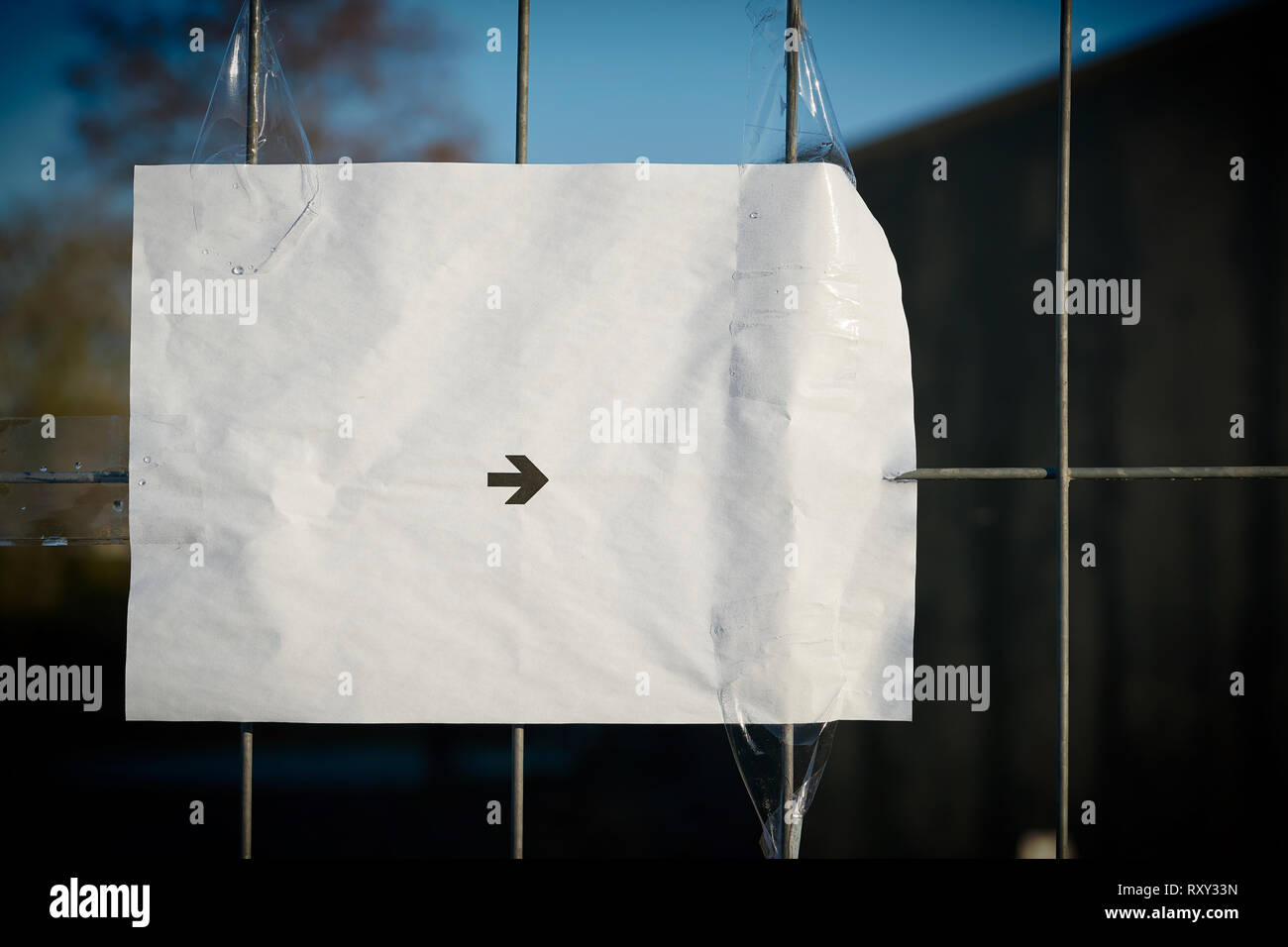 Sheet of paper with a directional arrow on a fence Stock Photo - Alamy