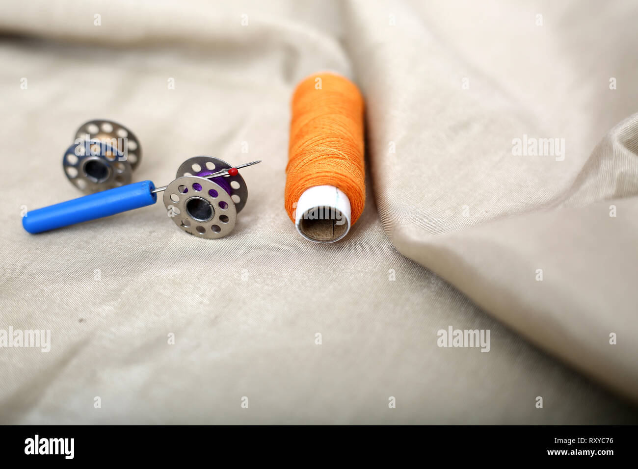 Picture of orange thread, needle ripper and bobbin on the cloth Stock ...
