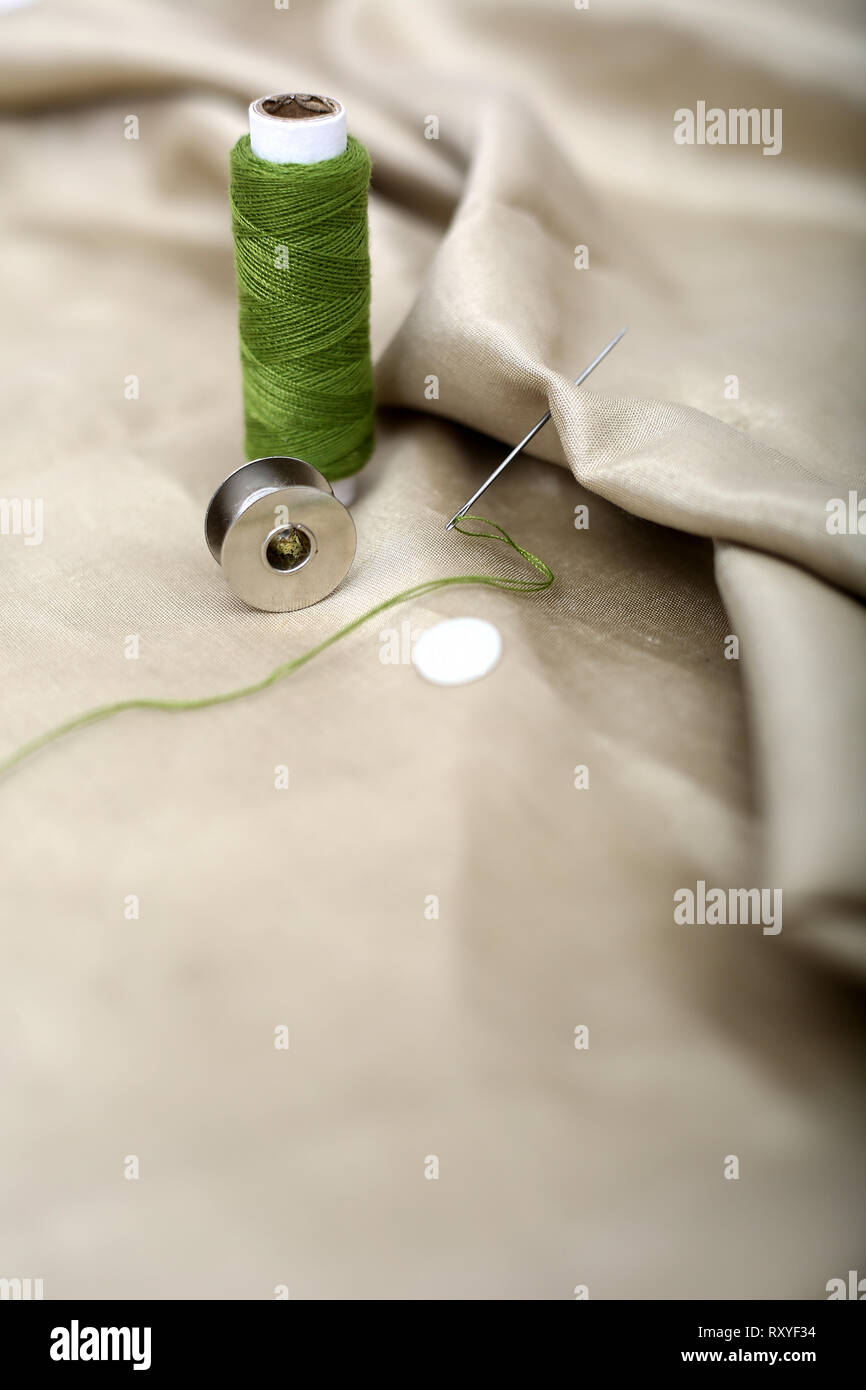 Picture of needle attached in cloth with green Sewing thread and bobbin ...