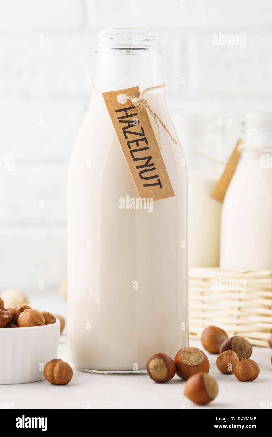 Hazelnut milk in a bottle with tag and raw ingredients. Light ...