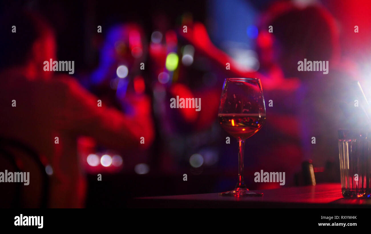 Bar with neon lighting. A person holding a glass of beer. Mid shot ...