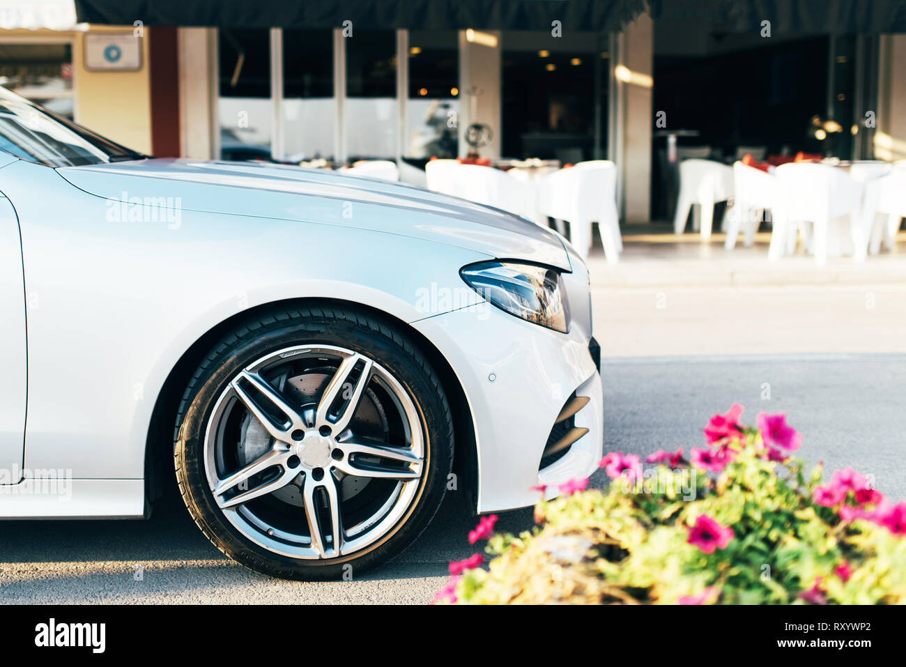 A white class business car is parked near a restaurant on the street ...
