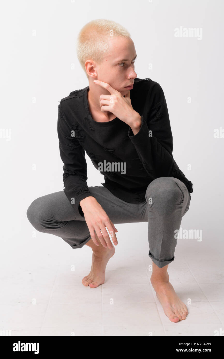 Full body shot of young thoughtful androgynous man crouching Stock ...