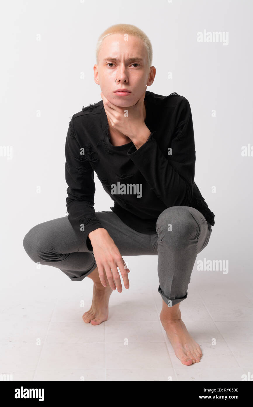 Full body shot of young androgynous man crouching Stock Photo - Alamy