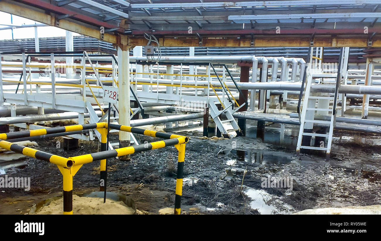 Spilled oil on sandy soil near pipelines and process equipment. Oil ...