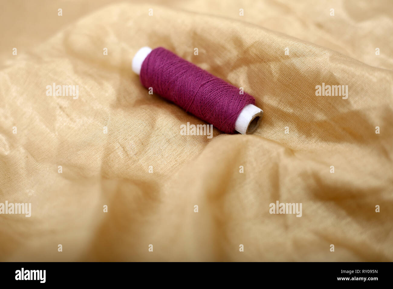 Picture of one sewing thread on the golden cloth Stock Photo - Alamy