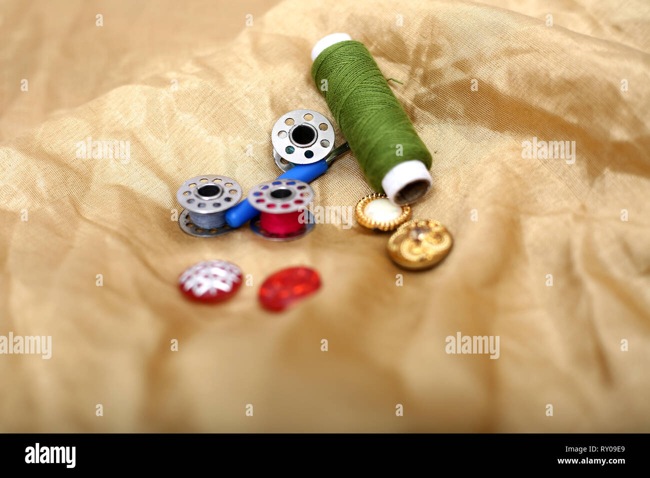 Picture of one sewing thread, needle ripper, button and bobbin on the ...