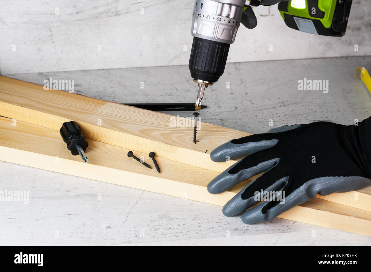 The builder holds in his hand an electric screwdriver on the background ...