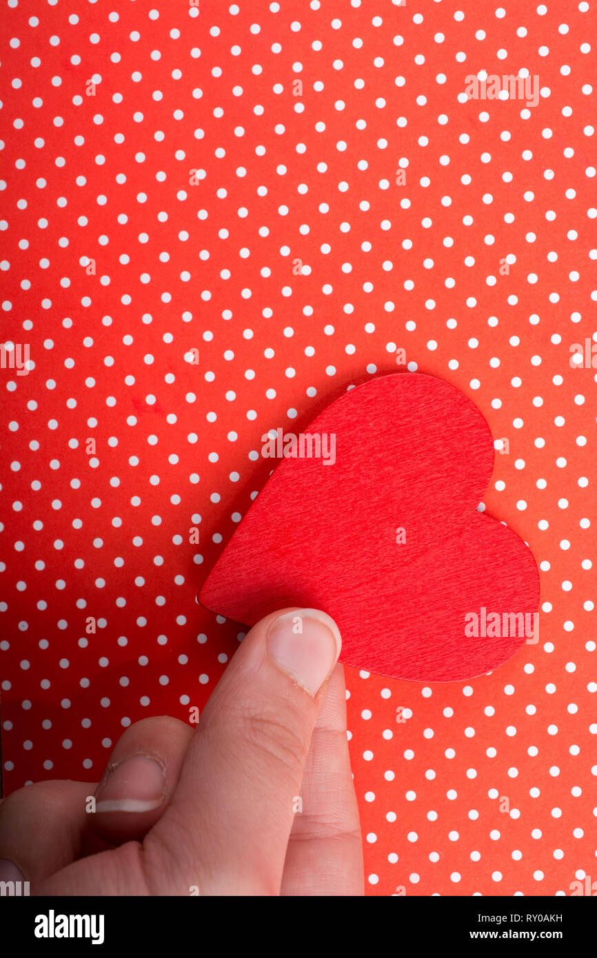 Red color heart shaped object in hand on dotted paper Stock Photo - Alamy