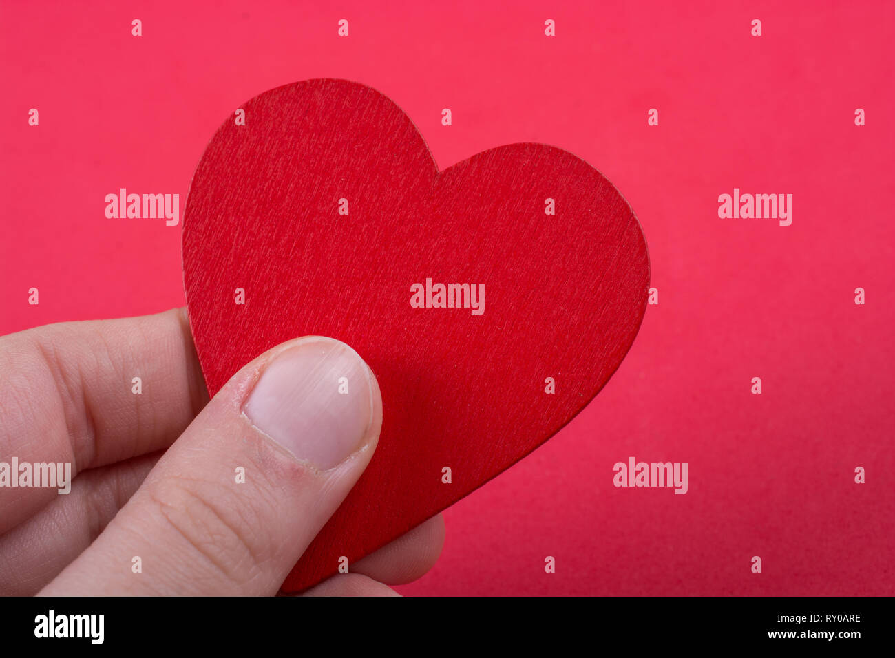 Red color heart shaped object in hand on dotted paper Stock Photo - Alamy