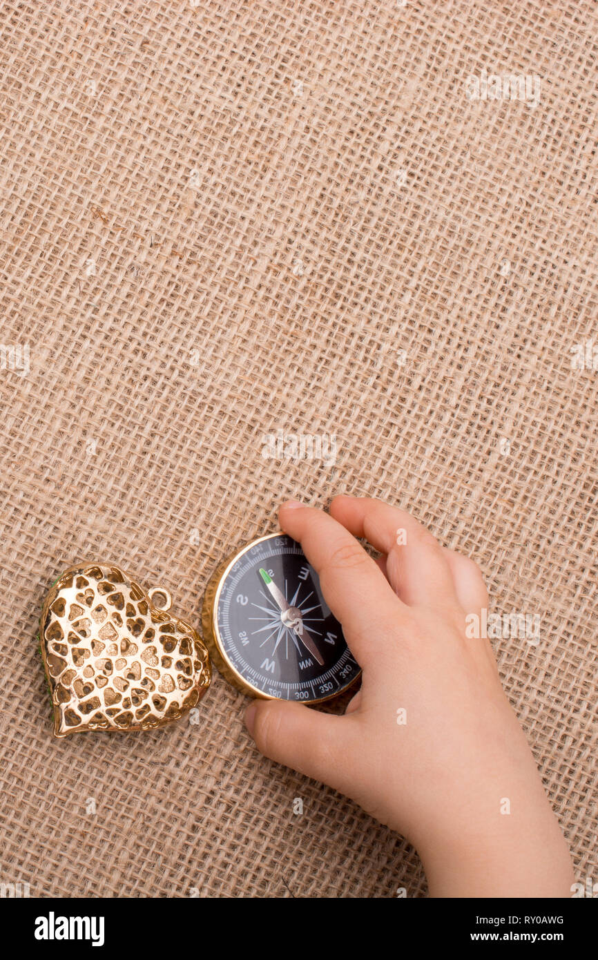 Compass, key and a heart shaped object beside a hand Stock Photo - Alamy