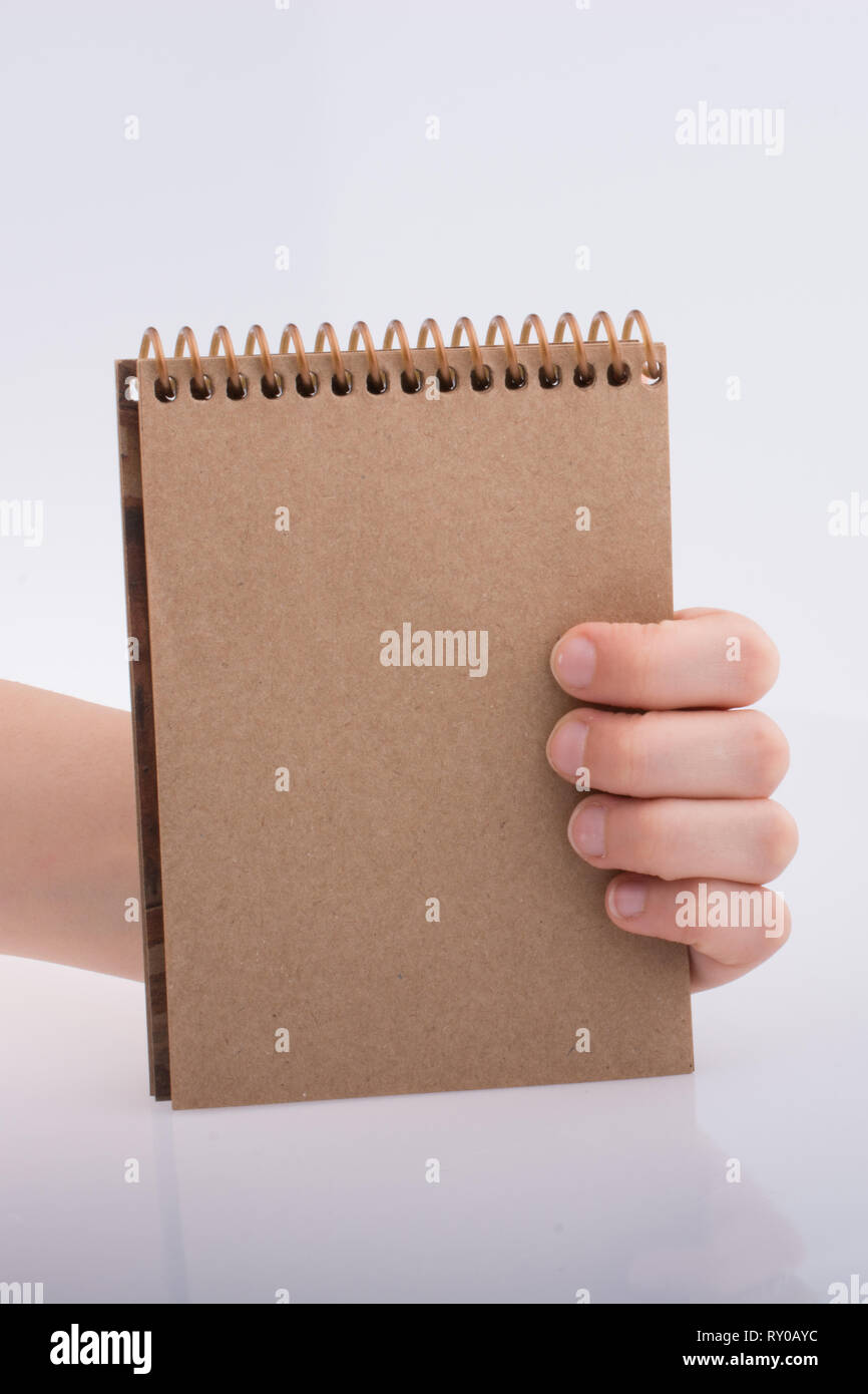 Hand holding a brown spiral notebook on a white background Stock Photo ...