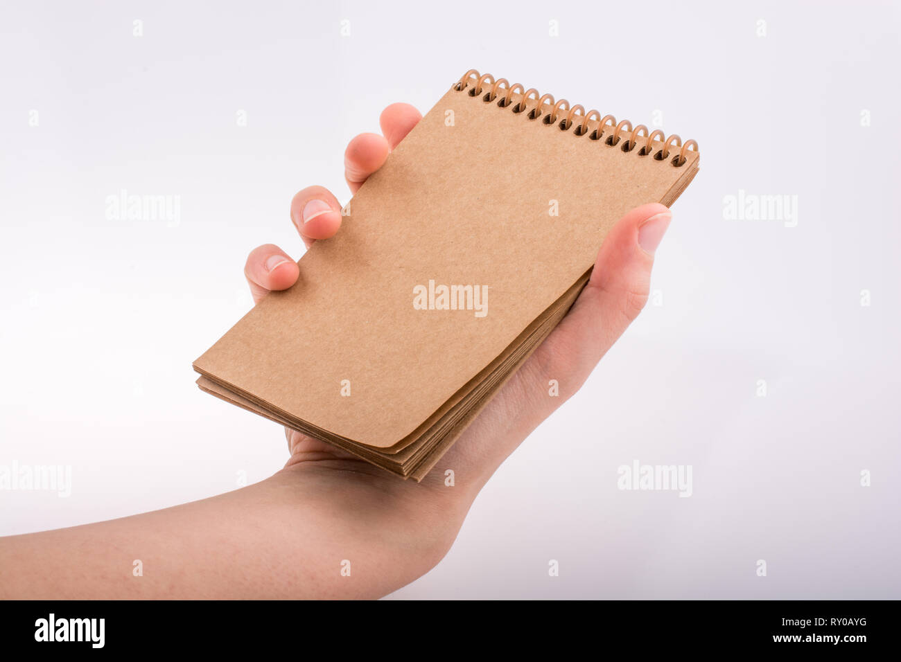 Hand holding a brown spiral notebook on a white background Stock Photo ...