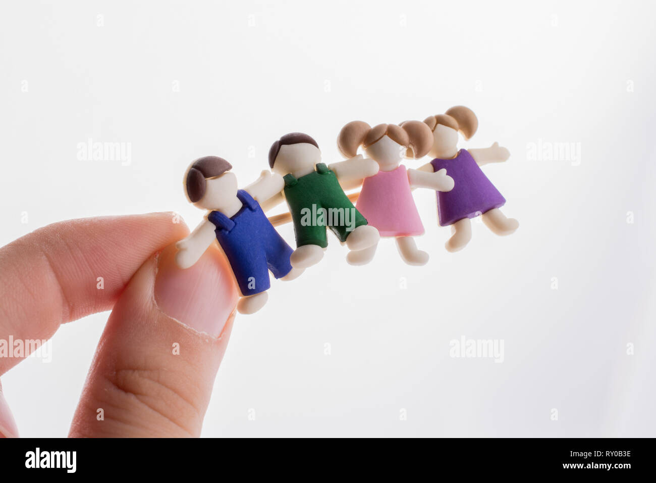 Little colorful boys and girls kid figurines in hand Stock Photo - Alamy