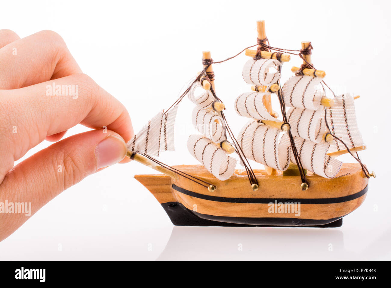 Hand in touch with a little model sailboat on a white background Stock ...
