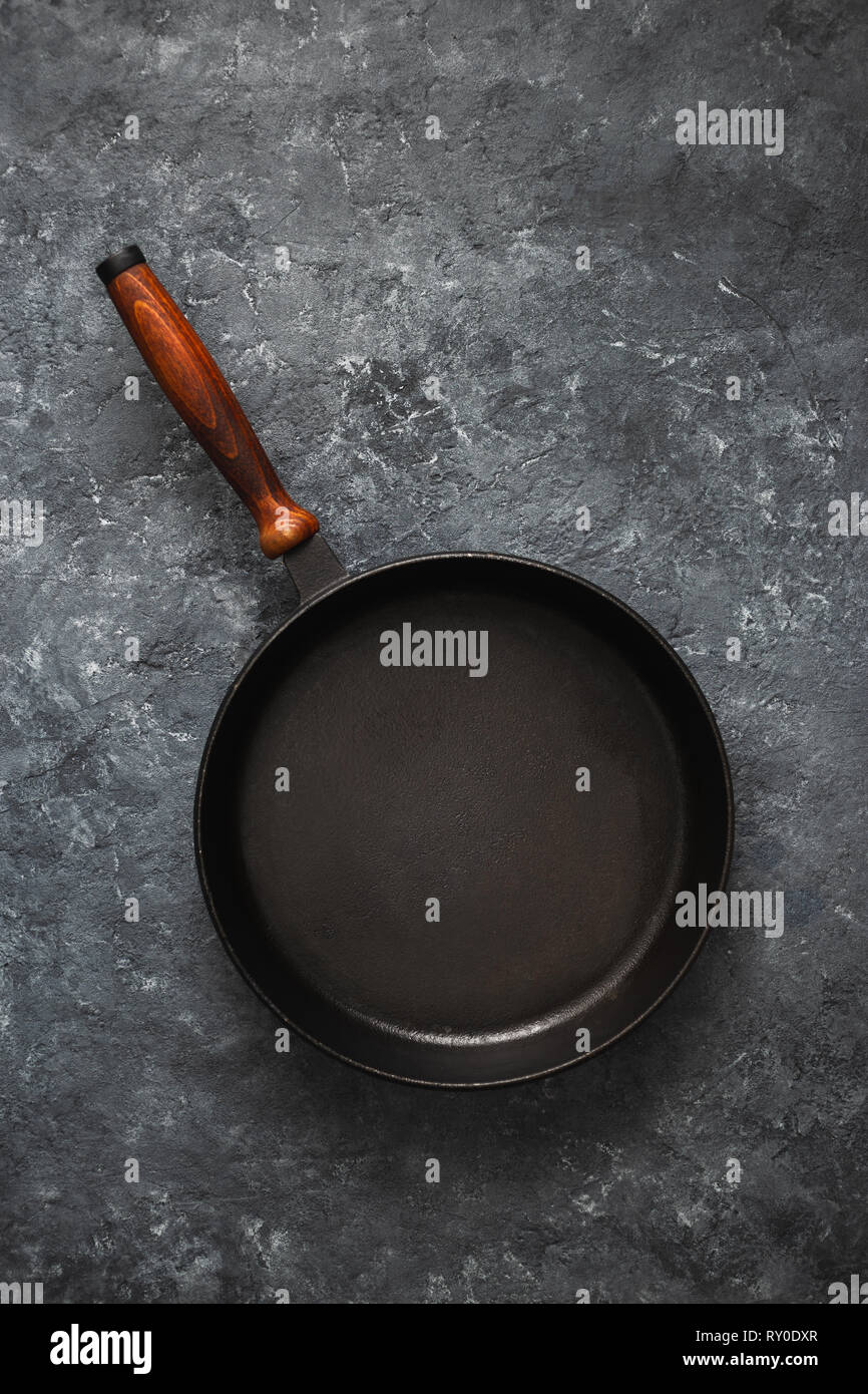 Empty round pan with wooden handle on dark stone background top view ...
