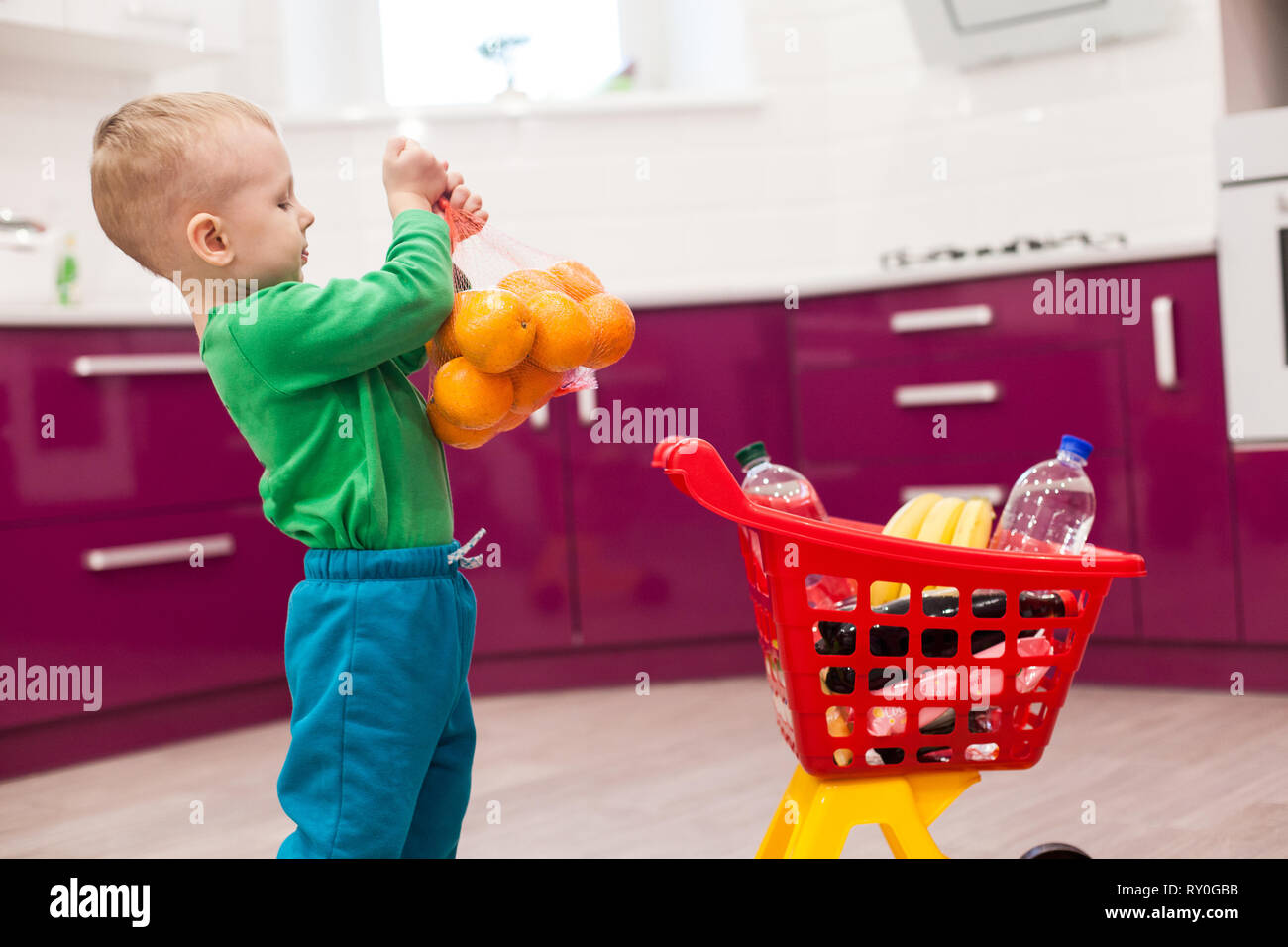 Little boy holds a grid with oranges. Little kid in casual wear ...