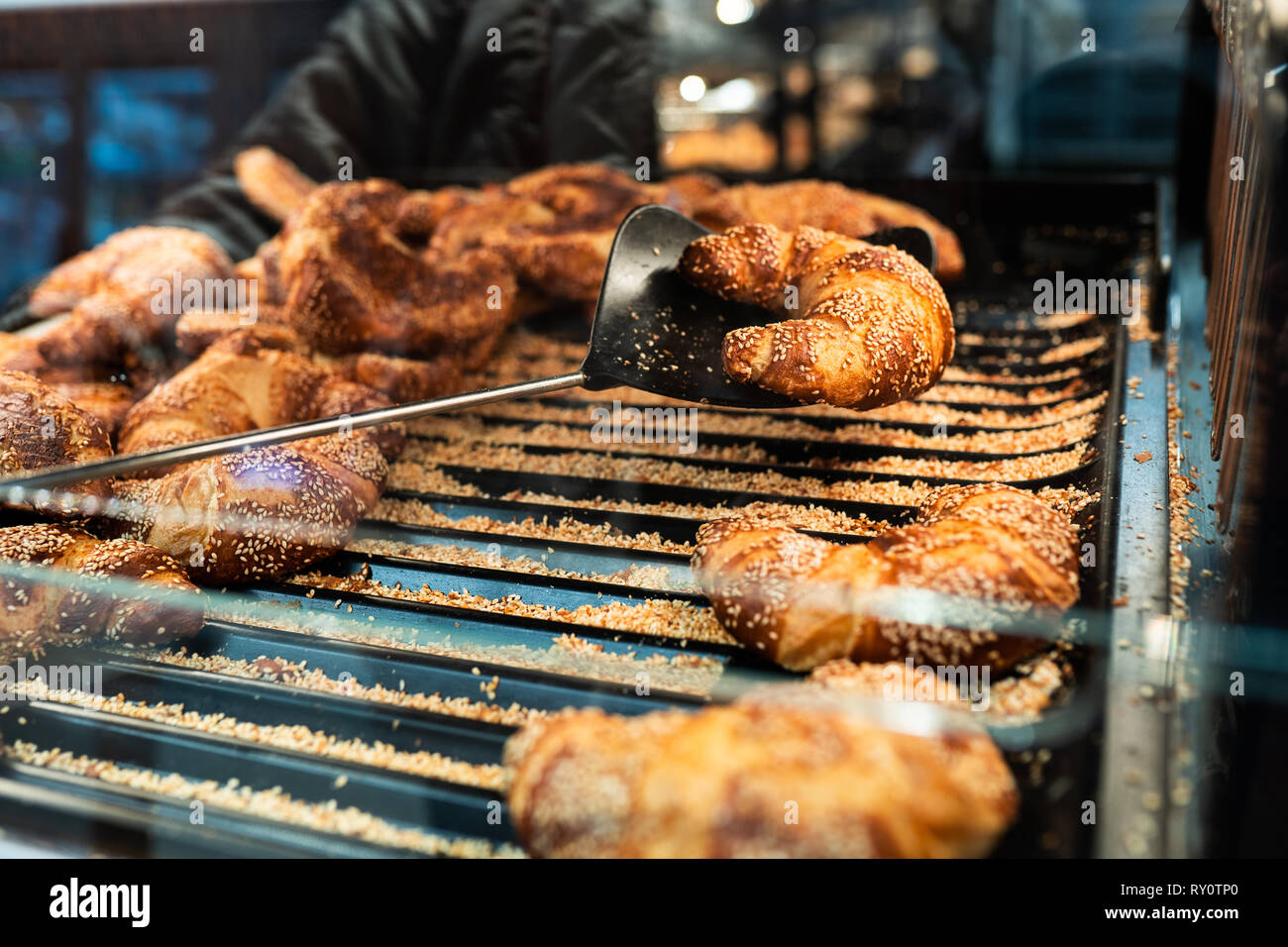 Fresh croissant on bread shelf in store. A man takes a fresh batch with ...