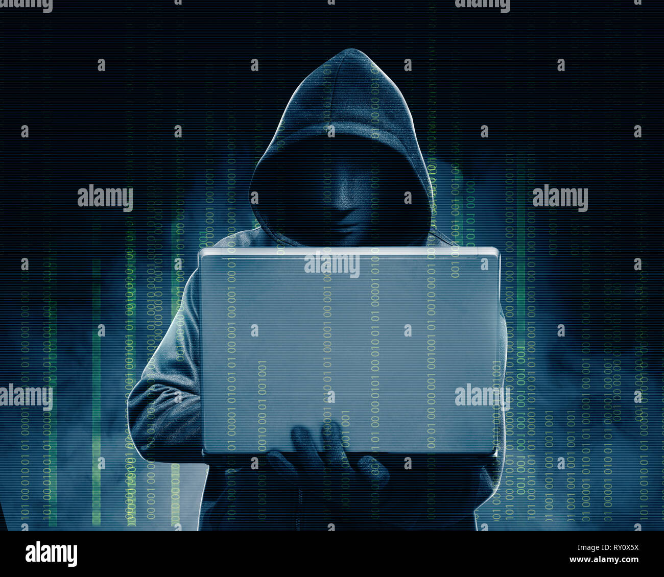 Hacker in black hoodie holding laptop with his hand and binary code ...