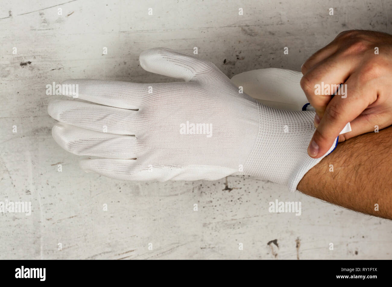 A man puts on a glove on his hand for repairs. Hand on light concrete ...