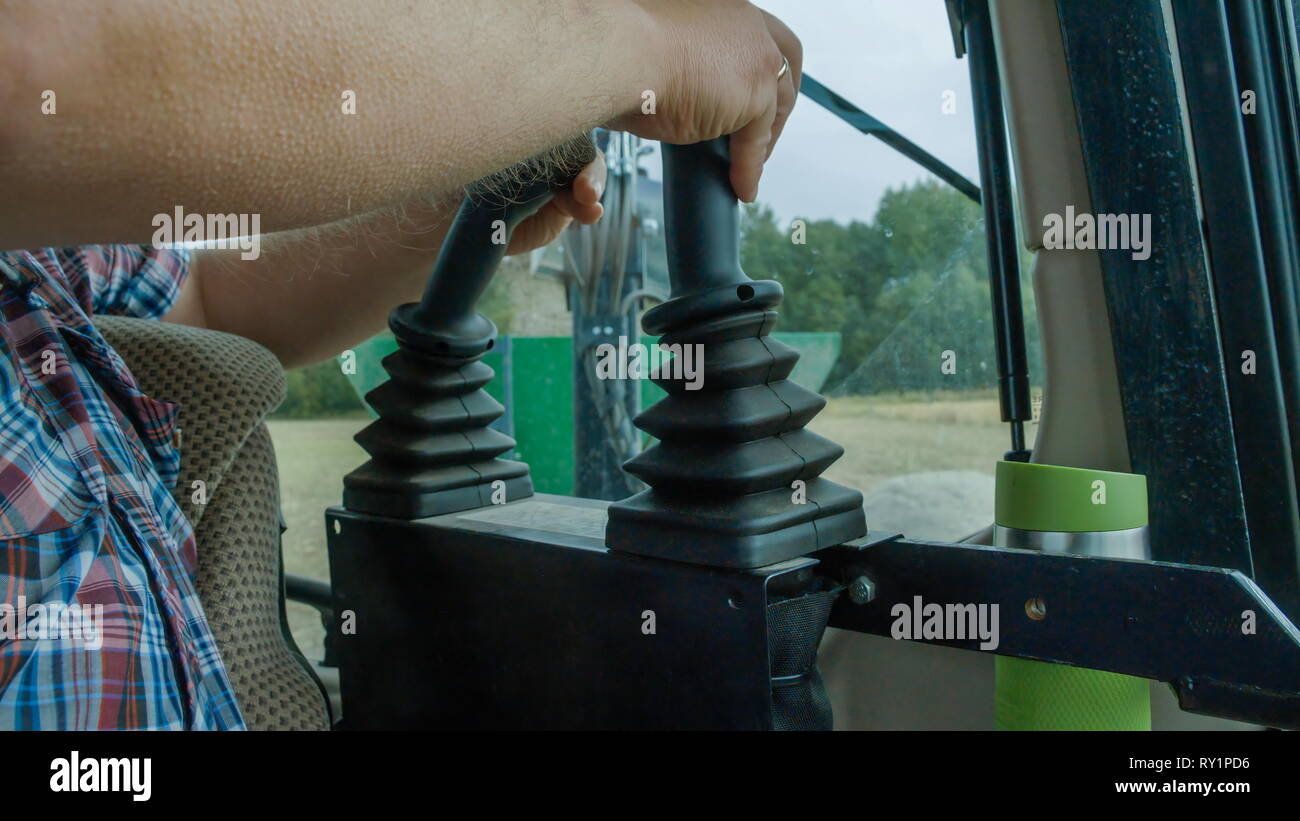 A man operating the backhoe in the quarry. Pushing the levers on the ...