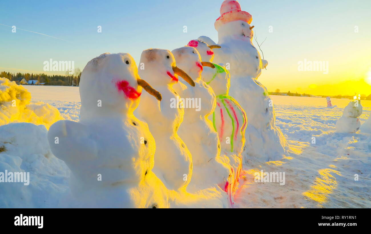 Five snowman aligned on the ground on a side view seen their long ...