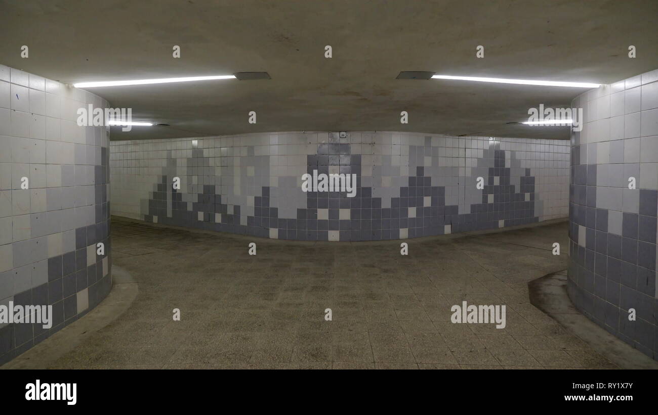 A two-way tunnel subway with gray brick walls the bricks have designs ...