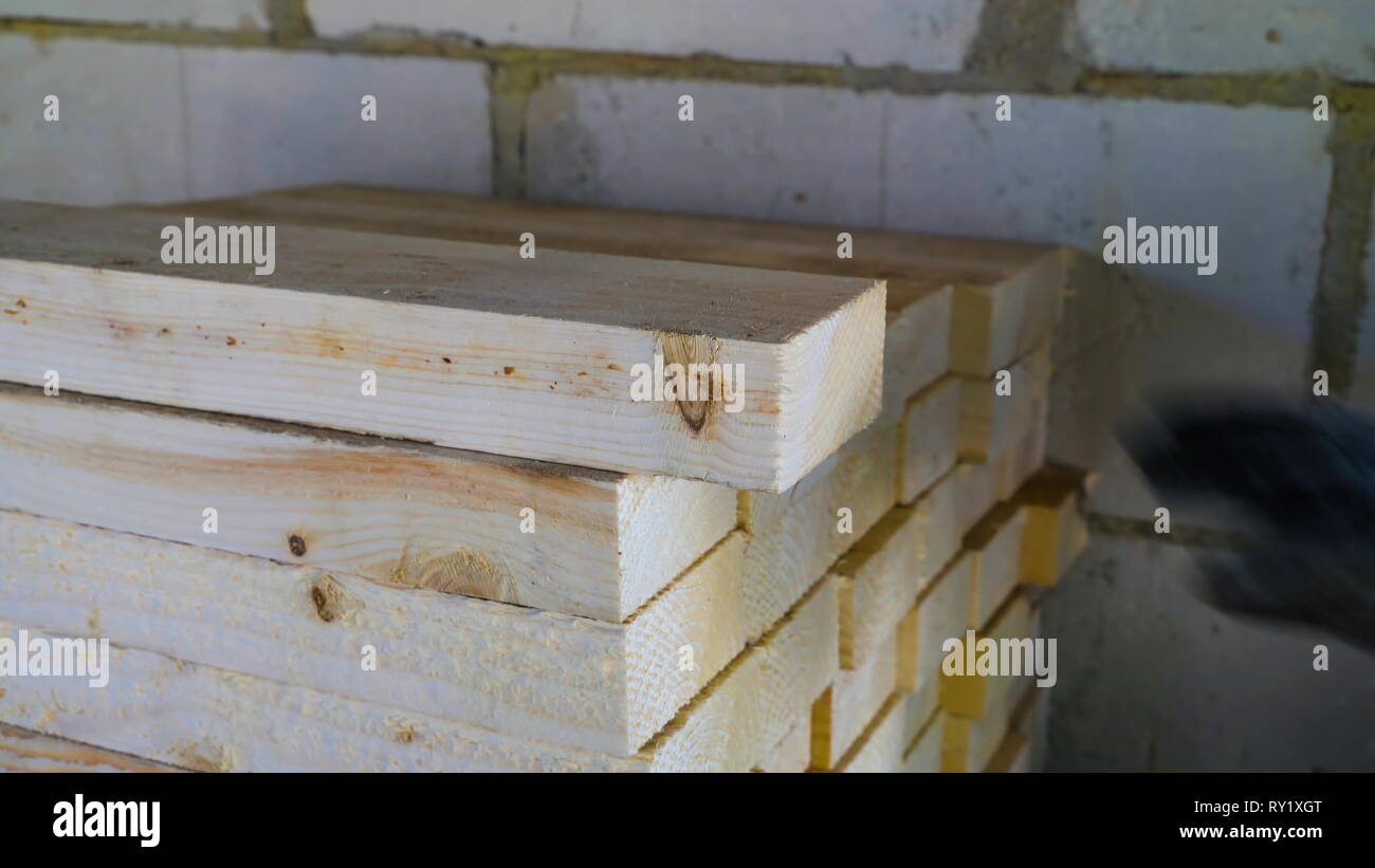 A lumber or wood being grabbed by a hand from the stacks of woods in ...