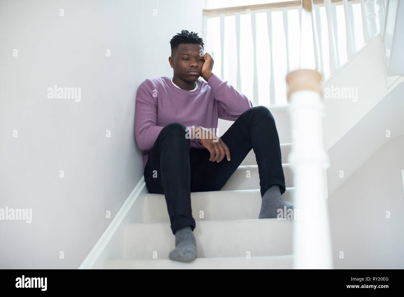 Fed Up Teenage Boy Sitting On Stairs At Home Stock Photo - Alamy