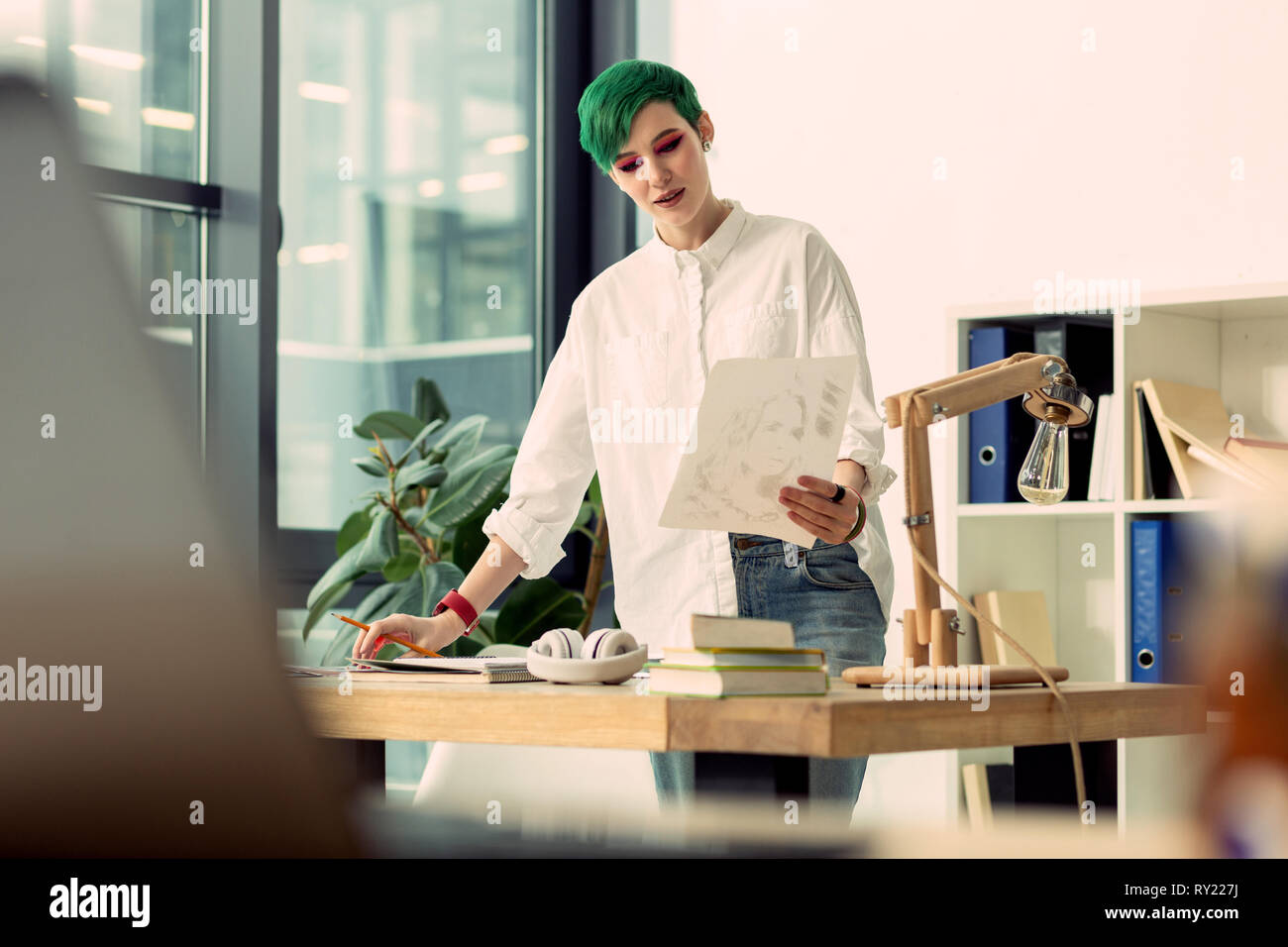 Pleasant creative woman looking at her drawing Stock Photo - Alamy