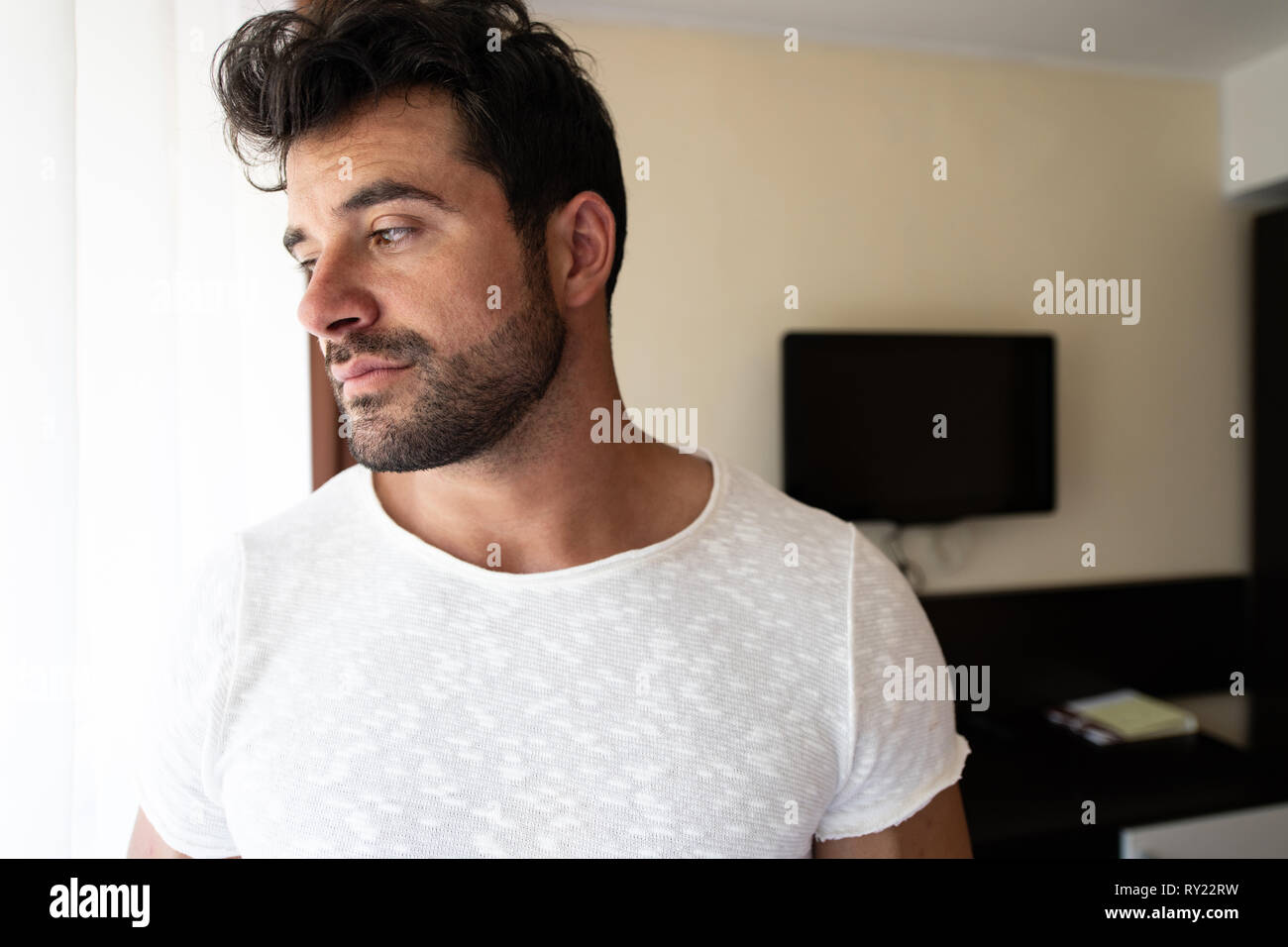 Young Man Standing at Window in Confident Pose Looking at City Stock ...
