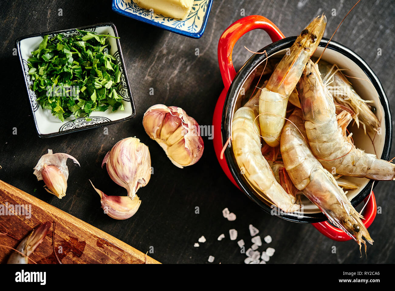 fresh delicious raw tiger prawns in a red pot with parsley, lemon ...