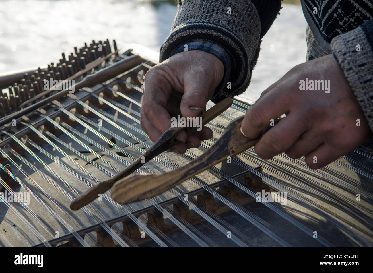 Hands dirty old street musician played on an old musical instrument ...
