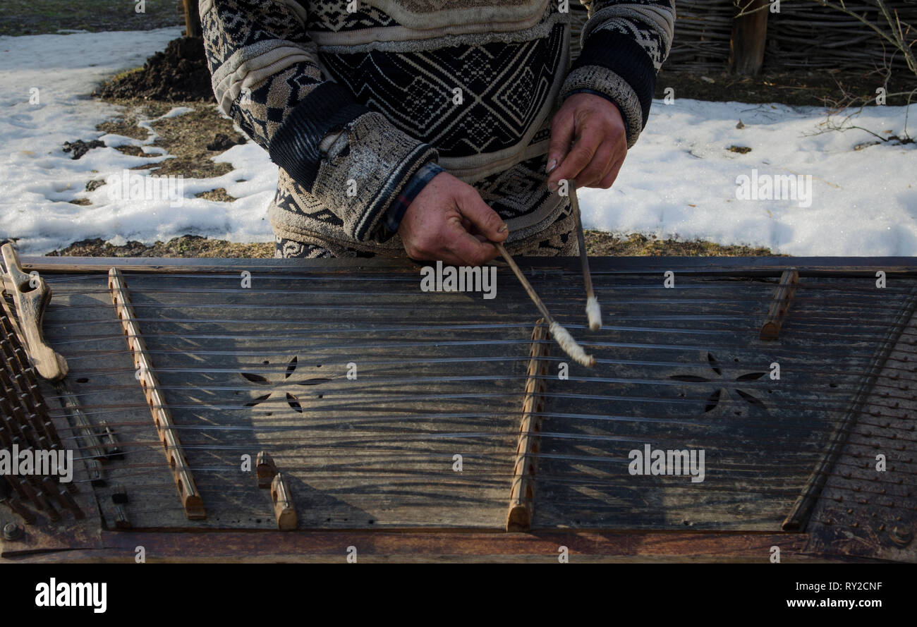 Hands dirty old street musician played on an old musical instrument ...