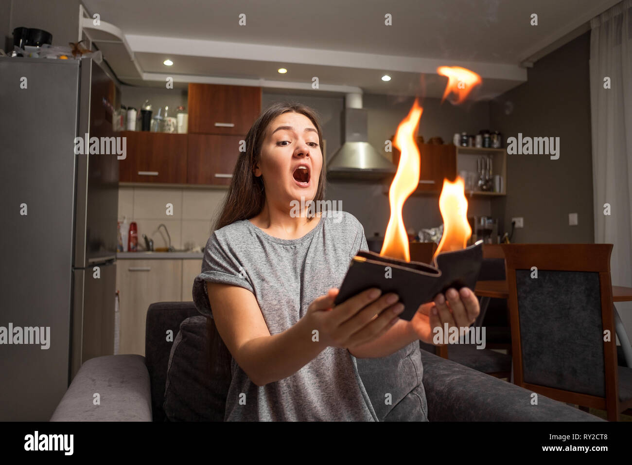 young woman holding a wallet, wallet on fire, surprised girl, magic ...