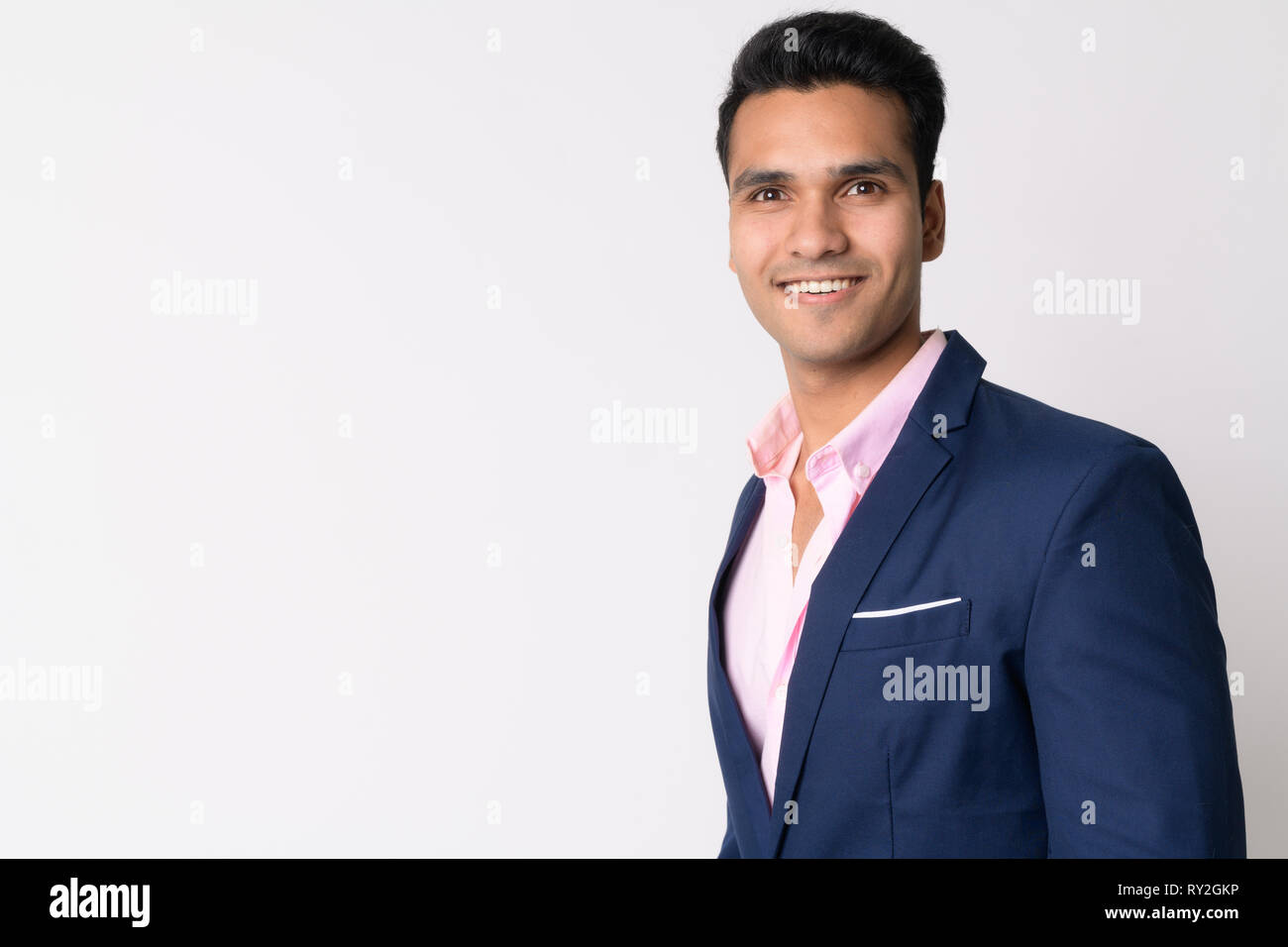 Profile view of young happy Indian businessman in suit looking at ...