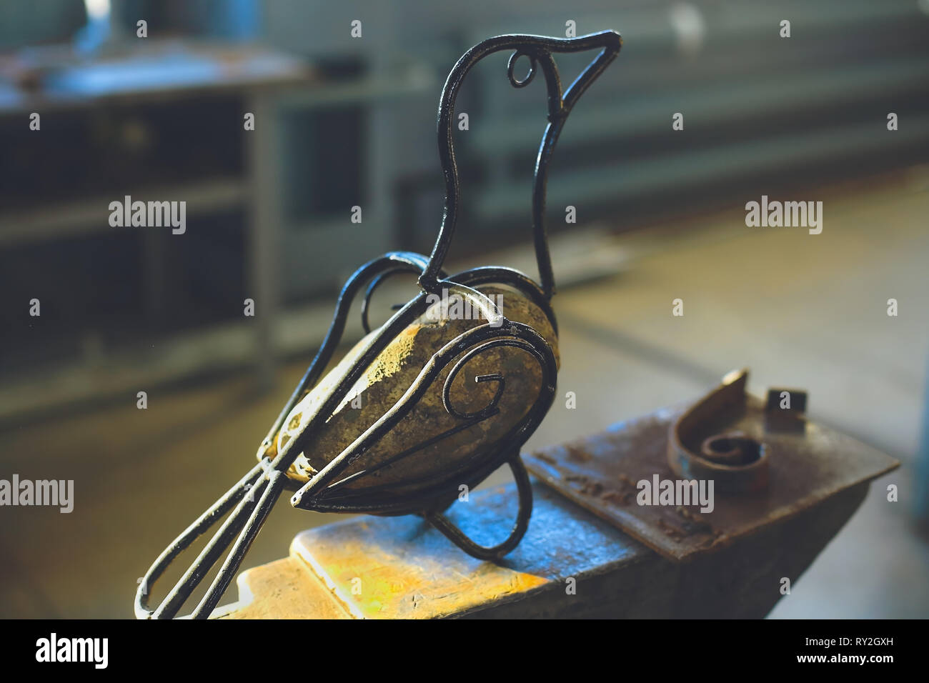 Homemade artificial bird of wire and stone body sitting on an anvil ...
