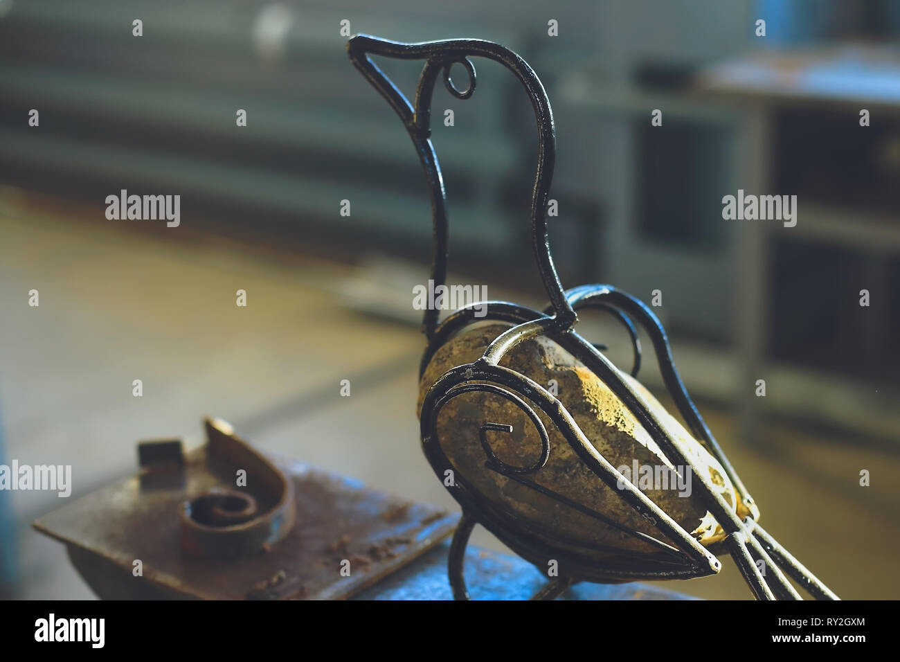 Homemade artificial bird of wire and stone body sitting on an anvil ...