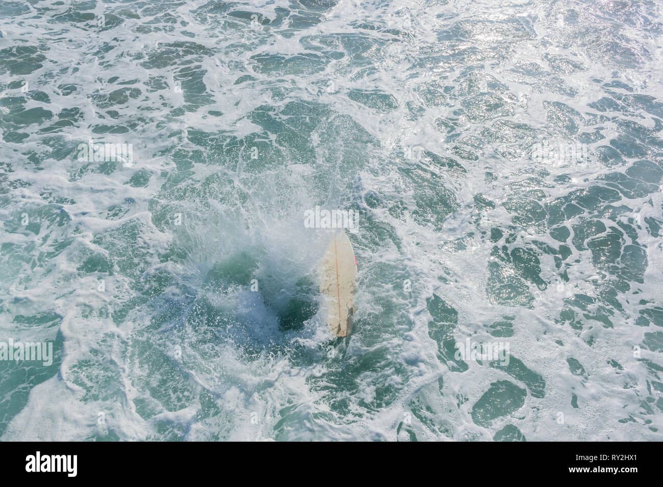 Surfer with surfboard jumps beach pier jetty into ocean water for quick ...