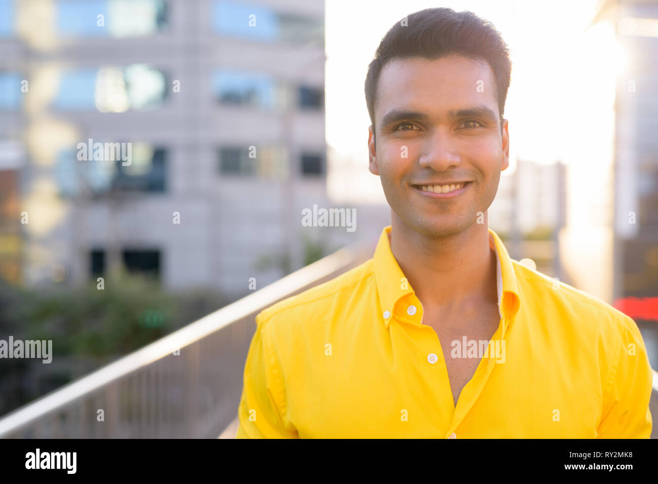 Face of happy young handsome Indian man smiling on the footbridge Stock ...
