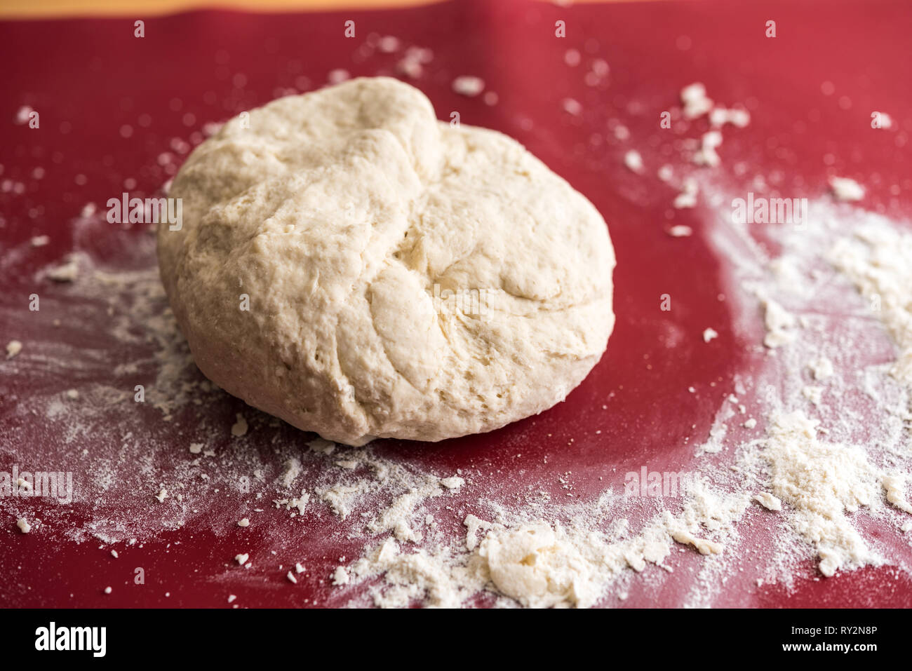 Homemade dough resting on red kneading mat Stock Photo - Alamy