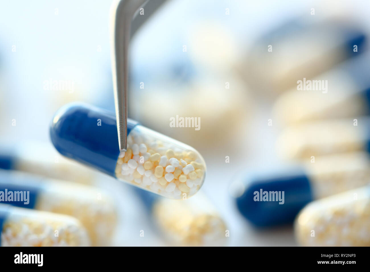 Arm lifting up pill with tweezers closeup Stock Photo - Alamy
