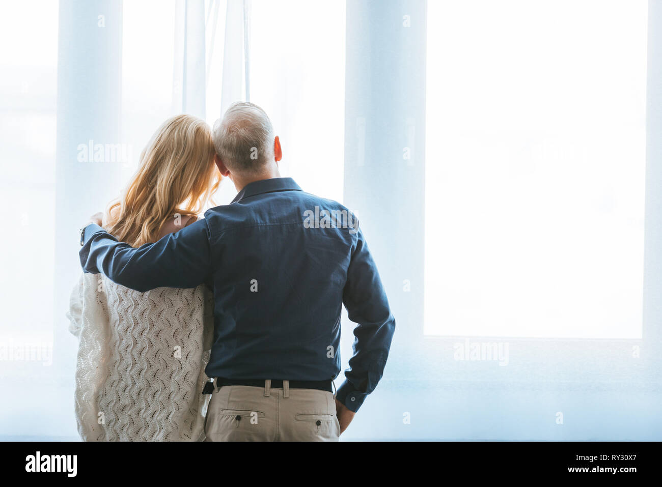 back view of couple hugging near window at home Stock Photo - Alamy