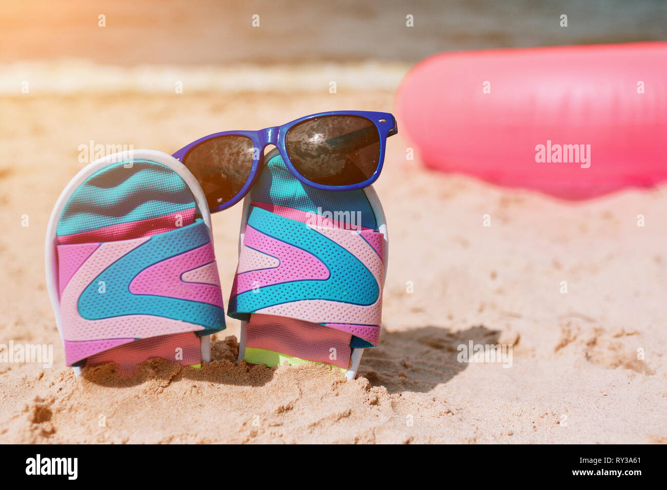 Flip-flops in sand on beach. Sunglasses on it. Summer vacation concept ...