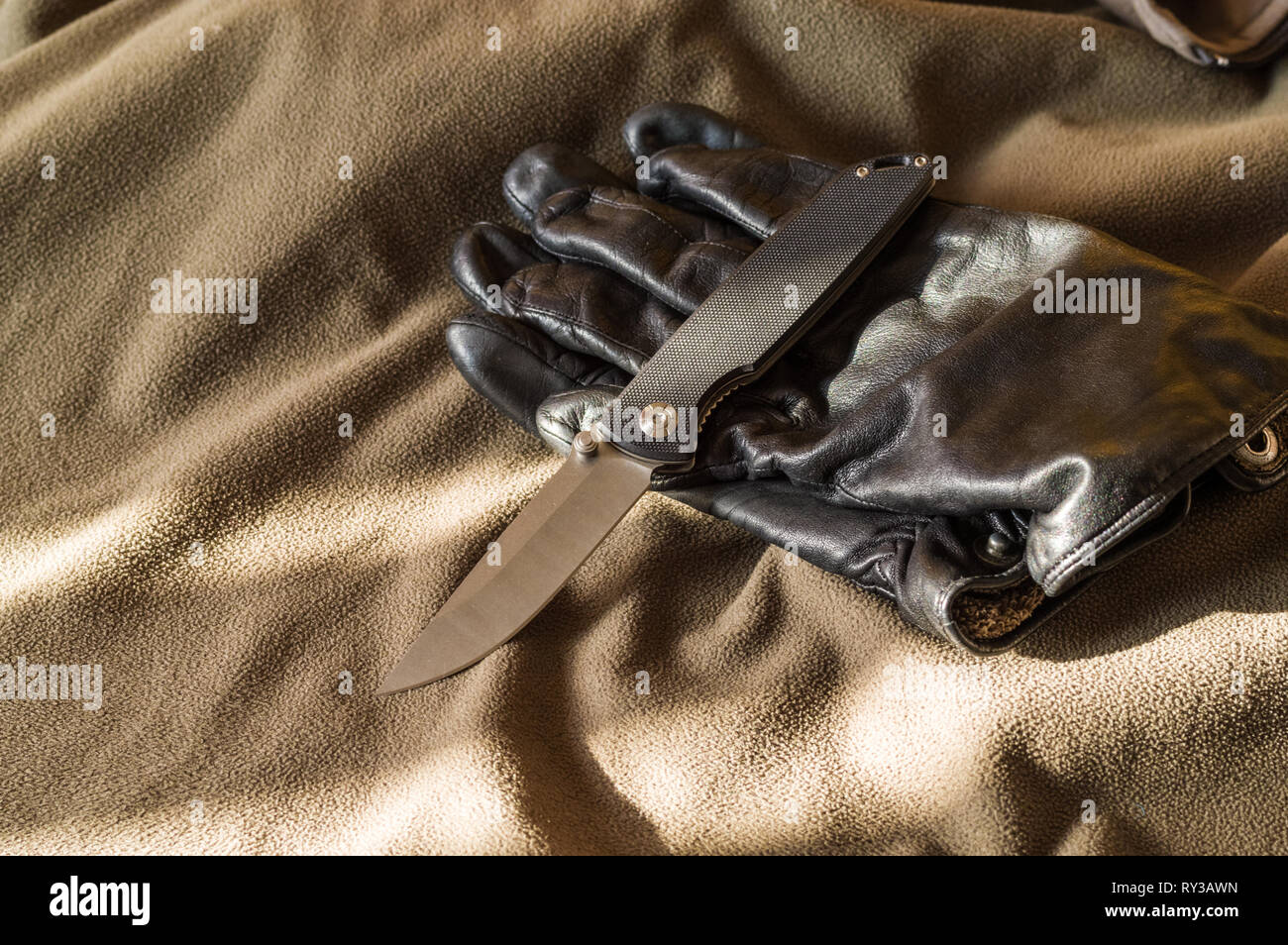Black folding knife and black handles. The sun's rays on the knife ...